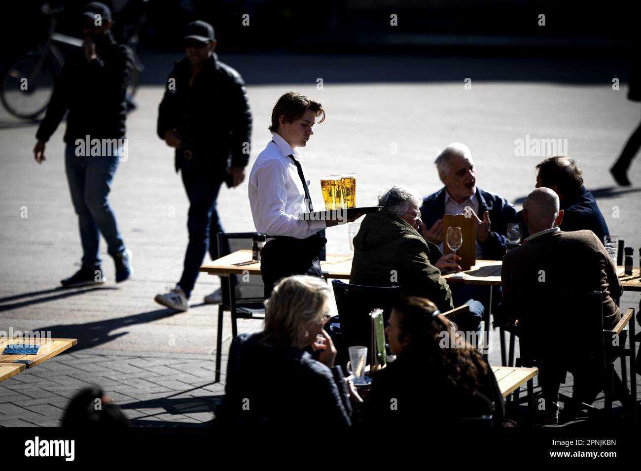 AMSTERDAM - A waiter serves beer on a terrace. ANP RAMON VAN FLYMEN ...