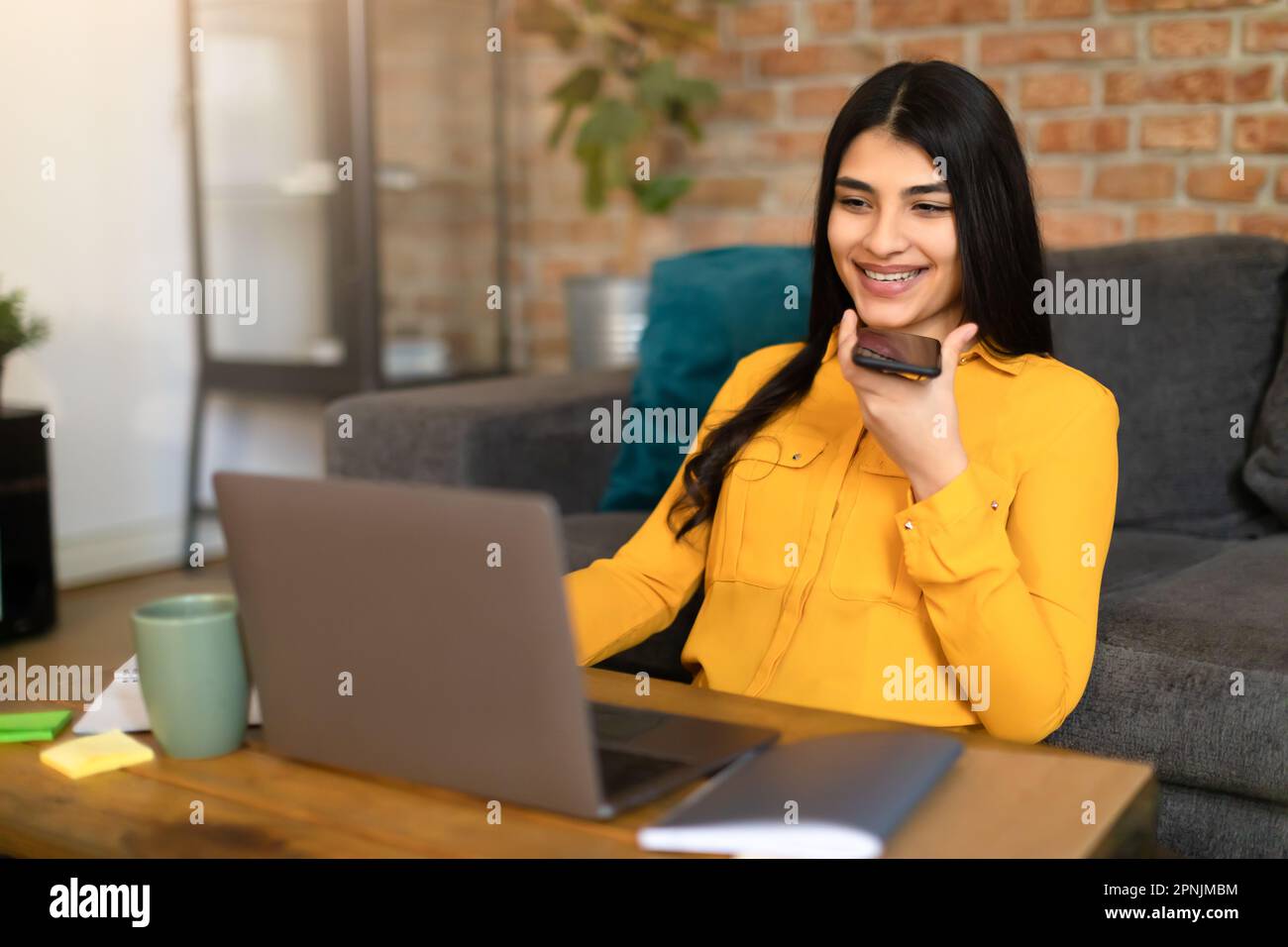Smiling spanish lady sitting at desk with laptop, talking on ...