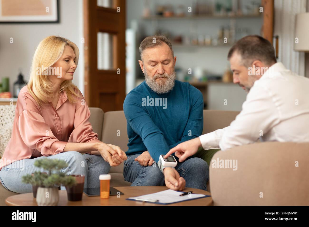 Doctor Measuring Blood Pressure With Medical Device For Couple Indoor ...