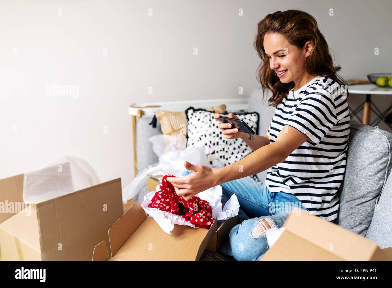 Curly woman taking picture of online purchase and posting photos on her ...