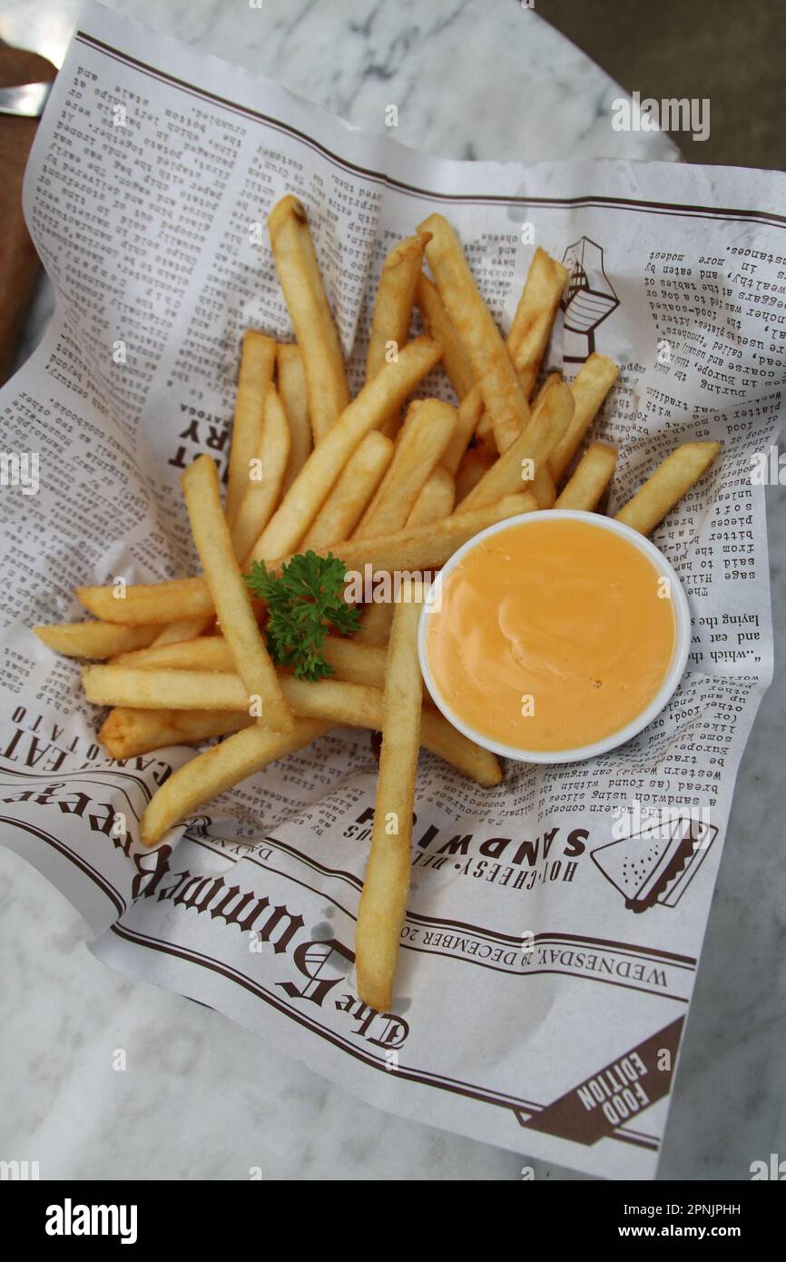 French fries on a paper with yellow cheese sauce Stock Photo - Alamy