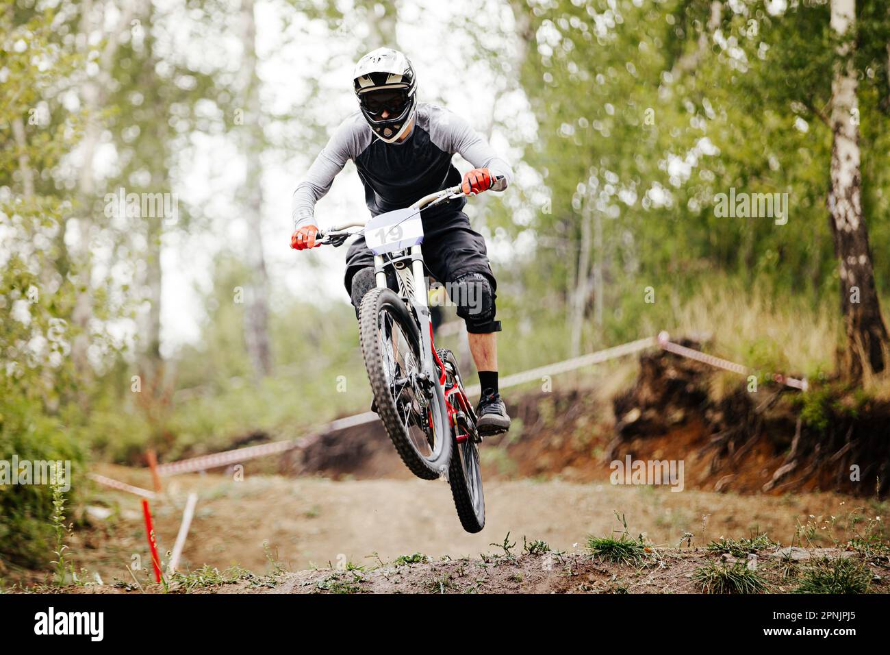 downhill mountain bike rider jump over springboard in forest trail race ...