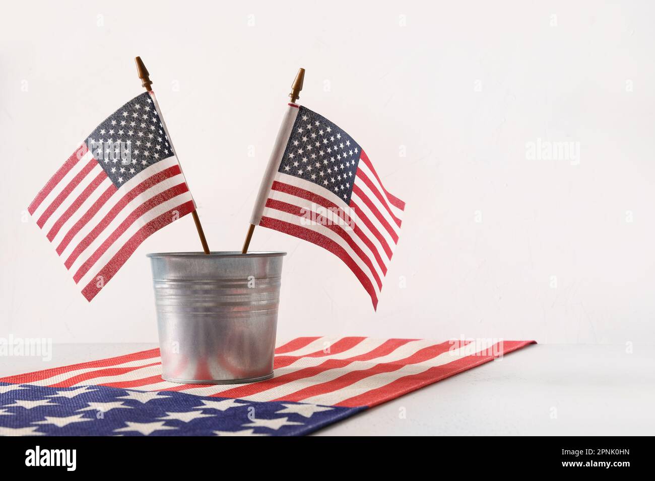 American flags in metal decorative bucket on white background. Concept ...