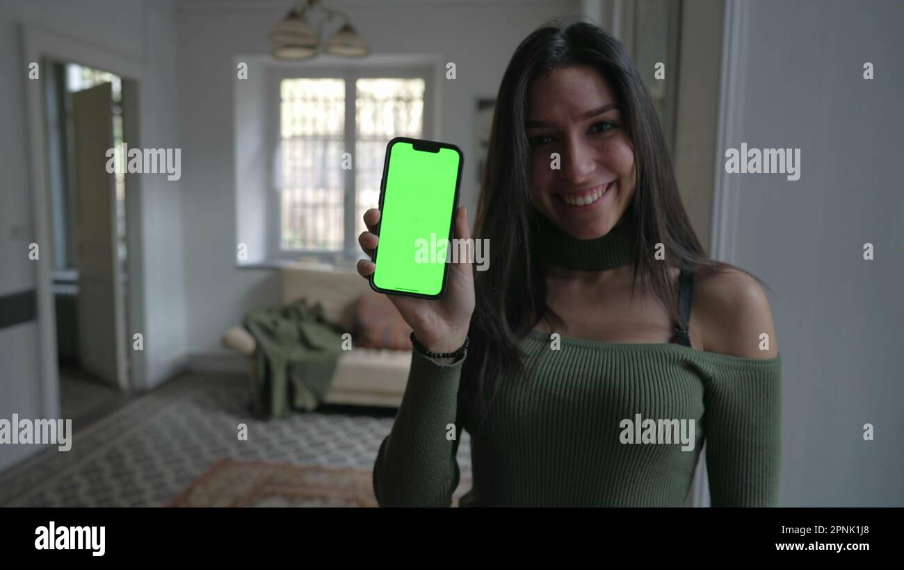 One happy young woman showing cellphone screen with chroma greenscreen ...