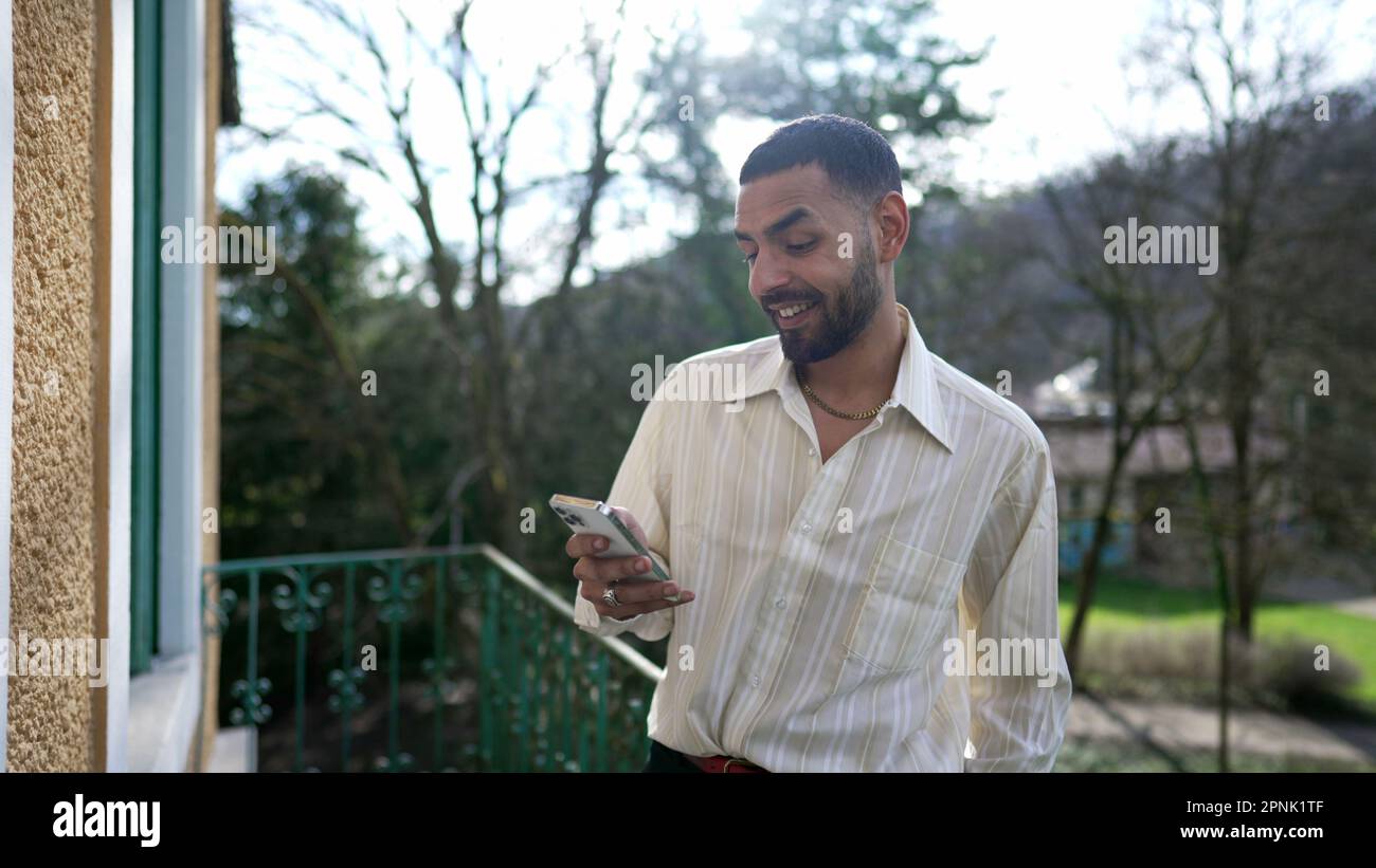 One Happy Arab young man looking at smartphone device screen standing ...
