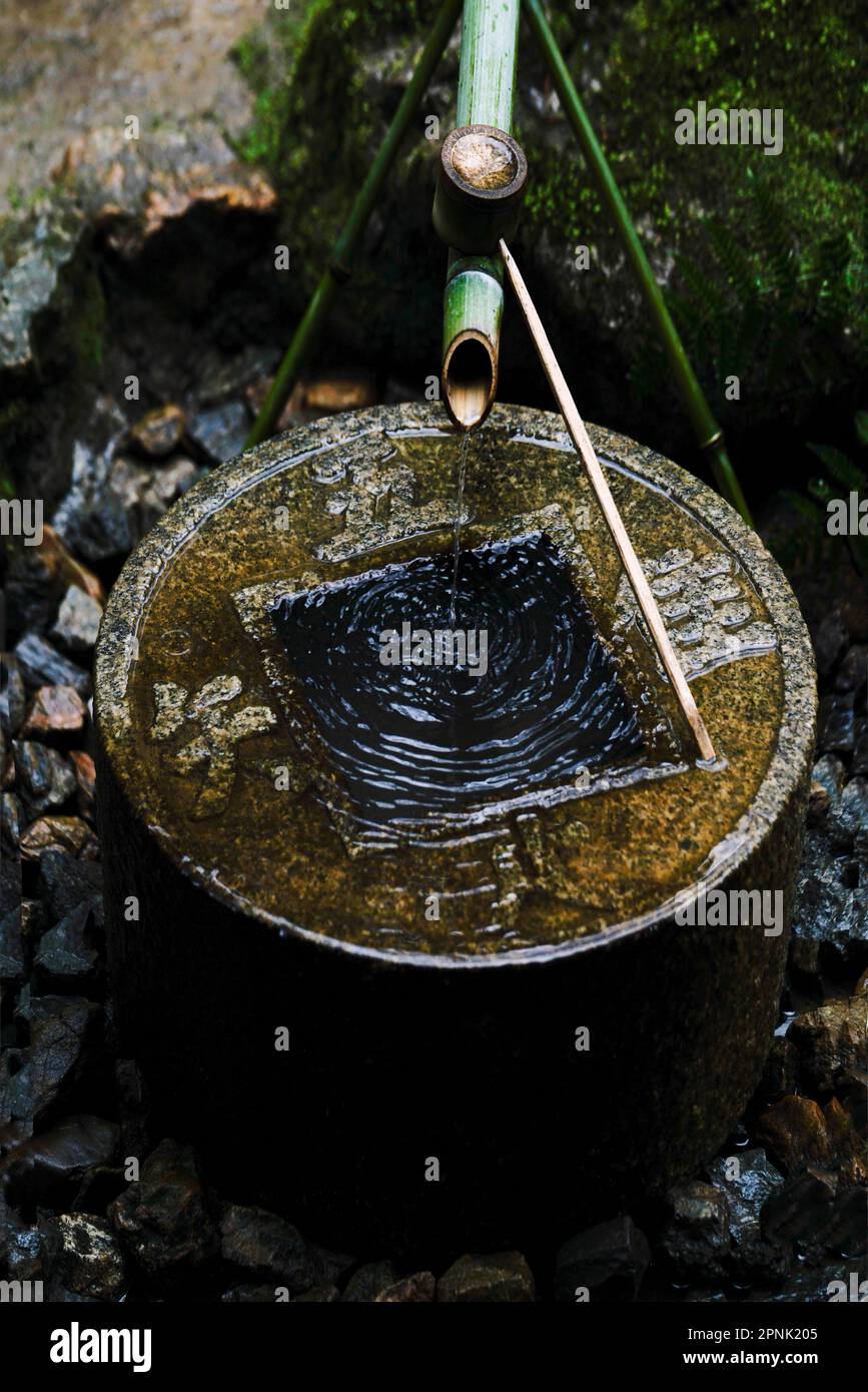 Tsukubai, or stone water basin, with a bamboo dipper, hisaku, for ...