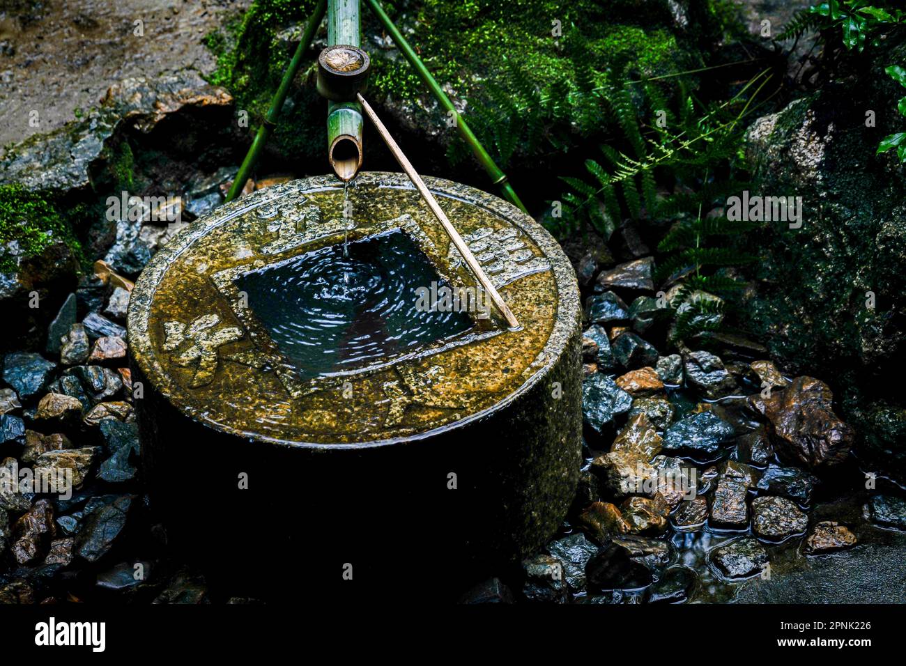 Tsukubai, or stone water basin, with a bamboo dipper, hisaku, for ...