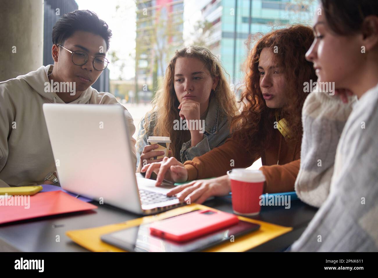 Focused group of young multiracial people using computer sitting on the ...