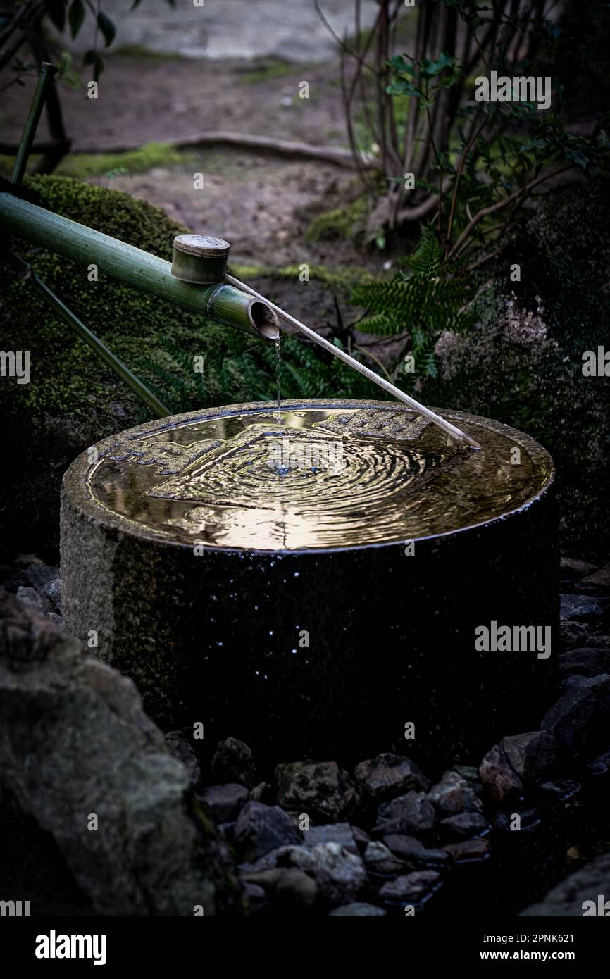 Tsukubai, or stone water basin, with a bamboo dipper, hisaku, for ...