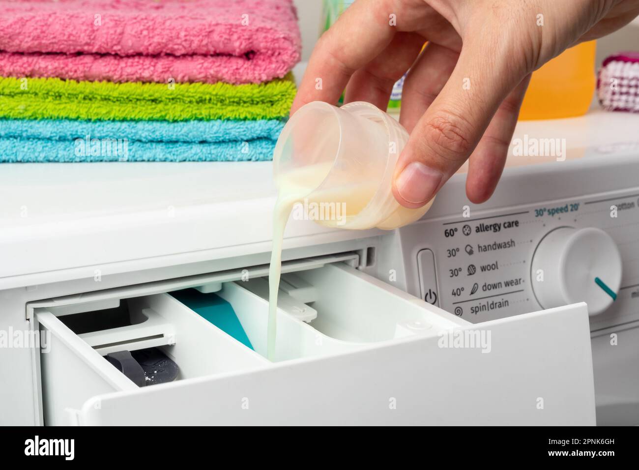Pouring the laundry conditioner into the washing machine. Laundry ...