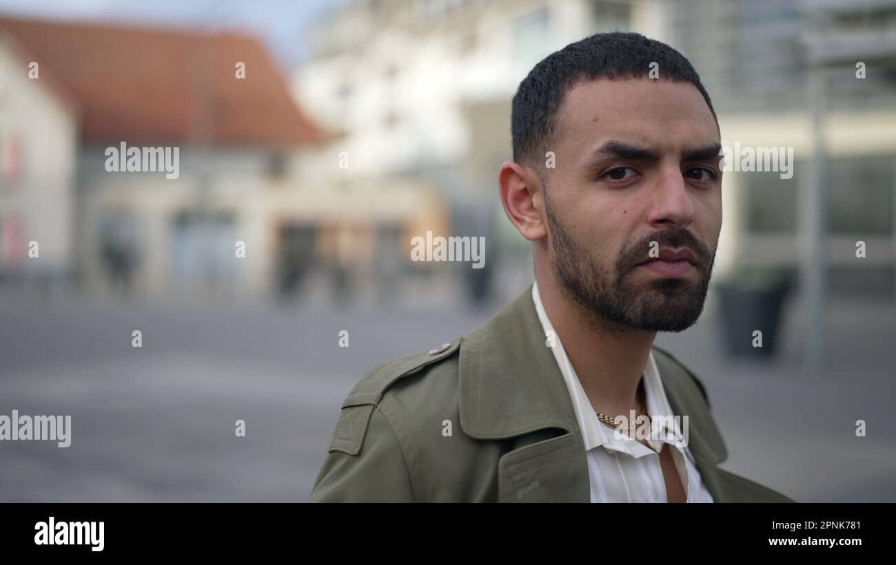 Portrait of a serious young Moroccan man looking at camera while ...