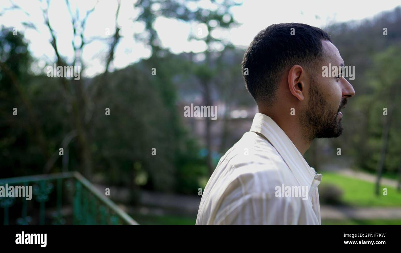One pensive young Middle Eastern man standing outside at balcony lost ...