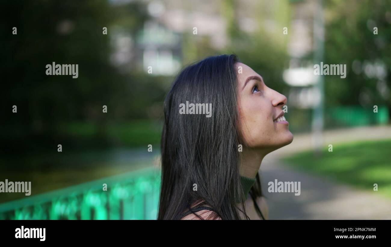 One smiling Middle Eastern young woman closeup face looking up at sky ...