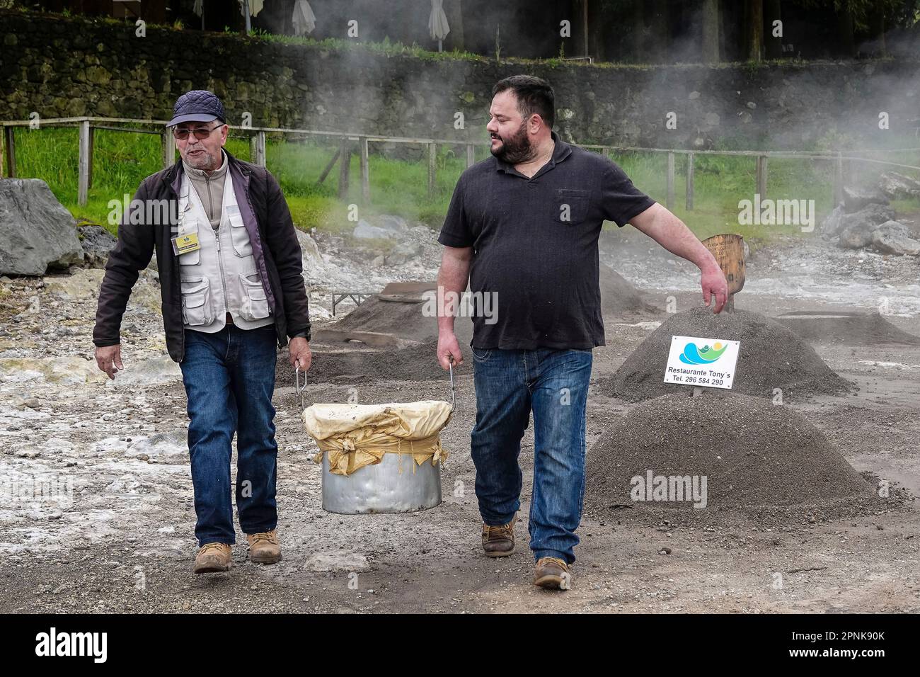 Workers carry a stew pot from a geothermal pit called a fumarole used ...