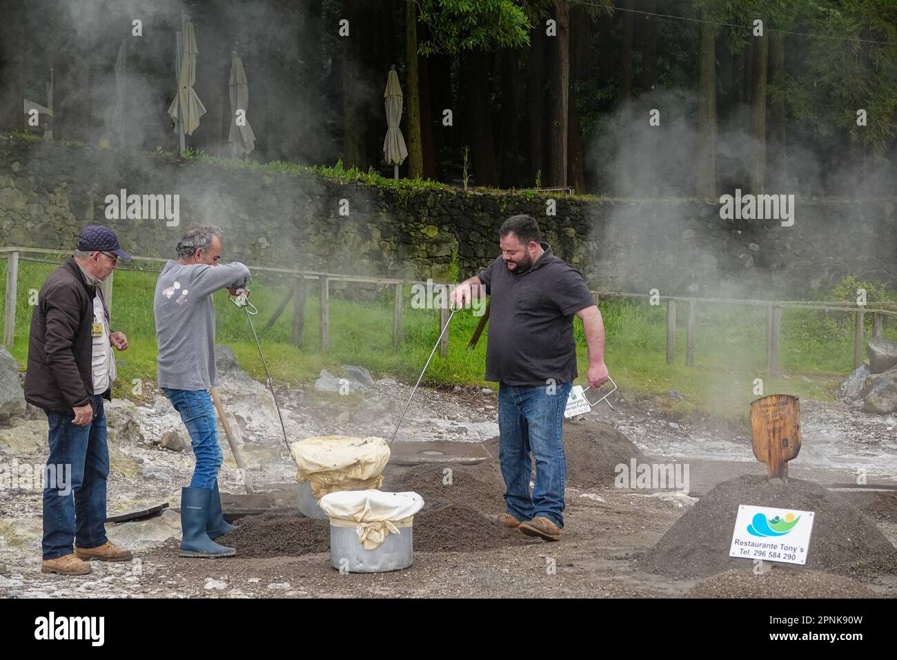 Workers lift a stew pot from a geothermal pit called a fumarole used to ...
