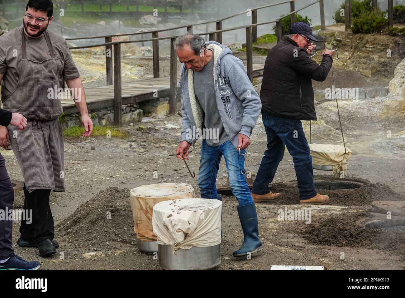 Workers carry a stew pot from a geothermal pit called a fumarole used ...
