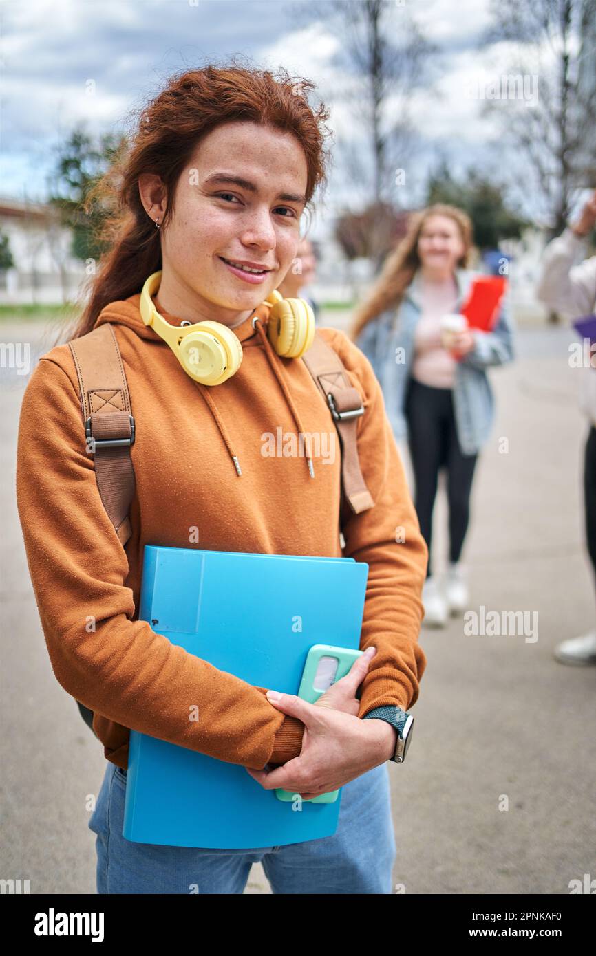 Vertical Red-haired college boy poses smiling looking at camera outside ...