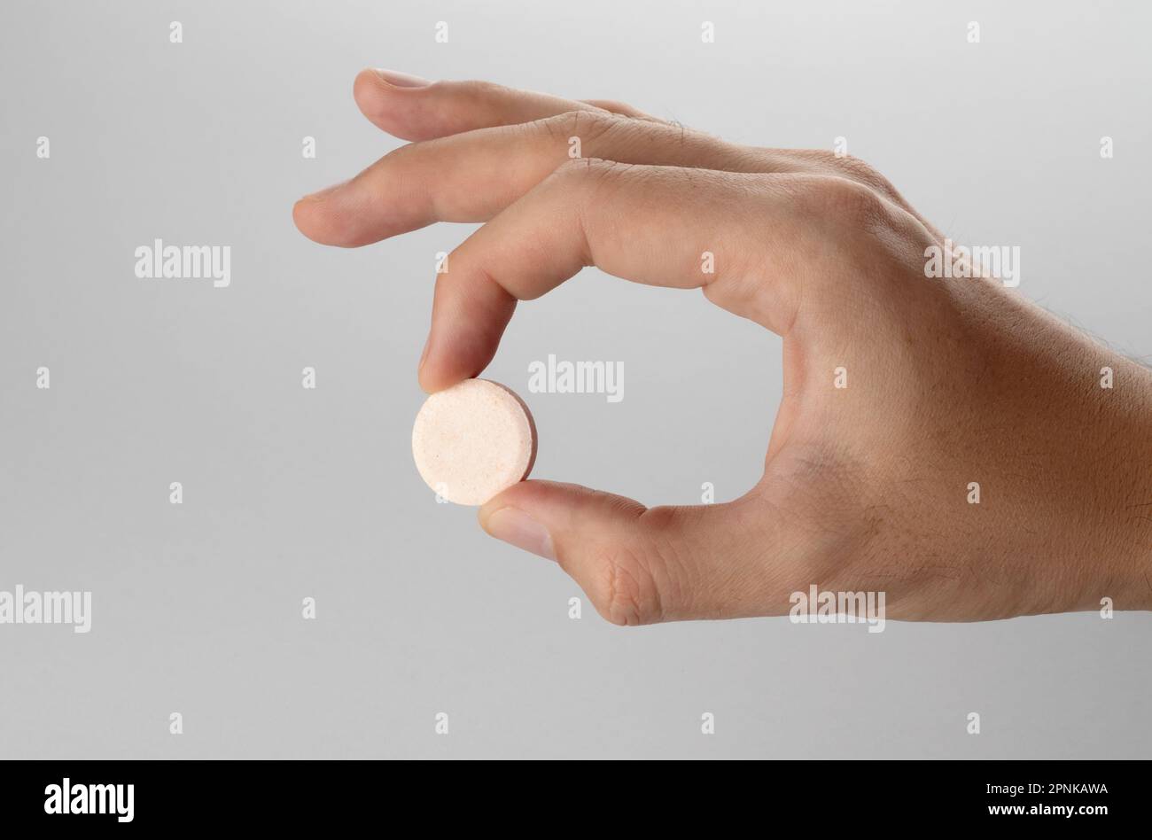 Male hand holding effervescent tablet in hand on grey background ...