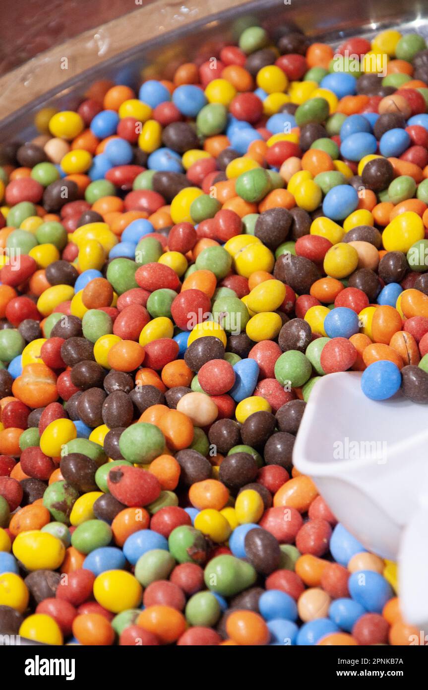 A large heart of bright multicolored round candies, dragees on a blue ...