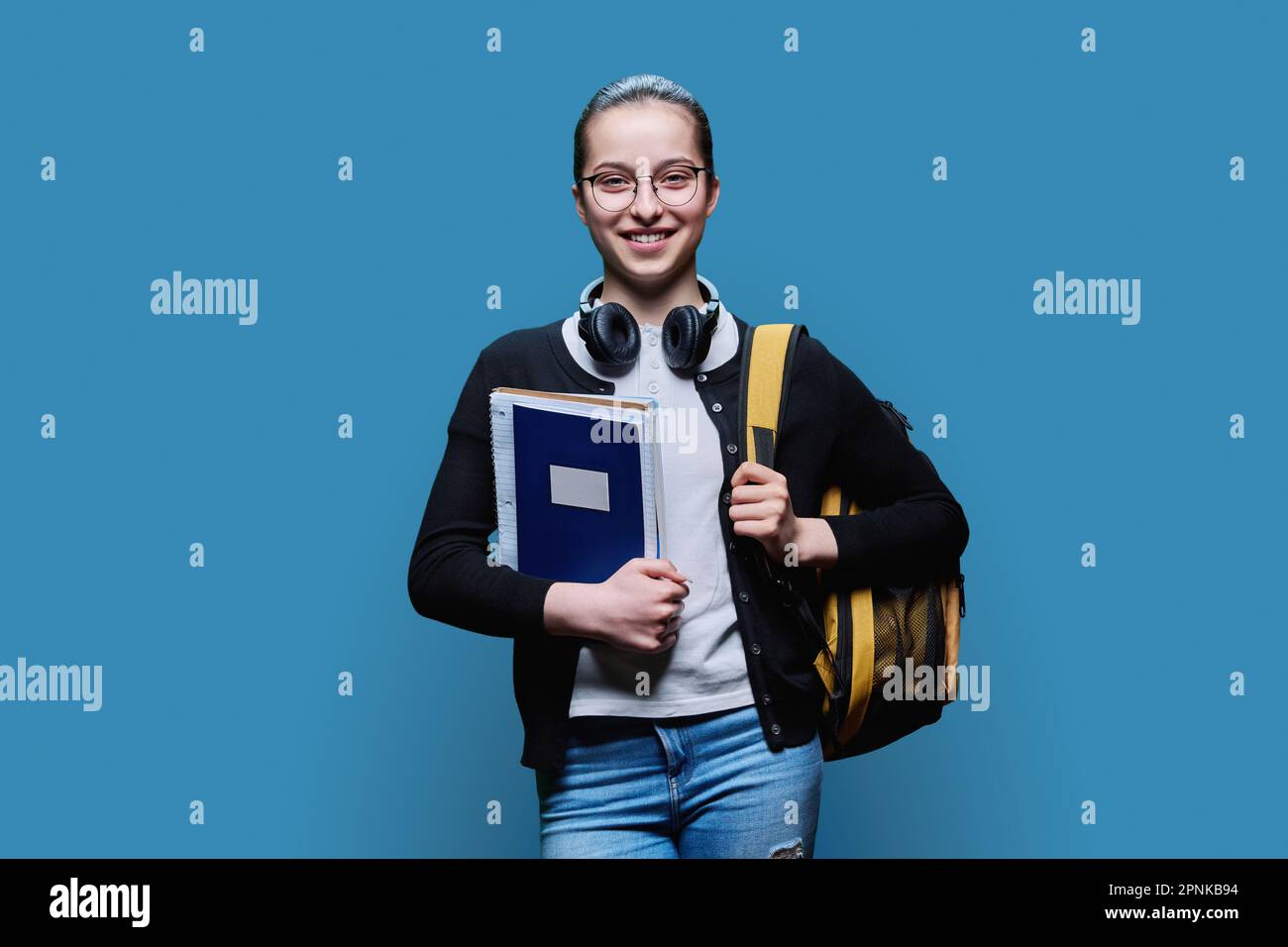 Portrait of teen girl high school student on blue studio background ...