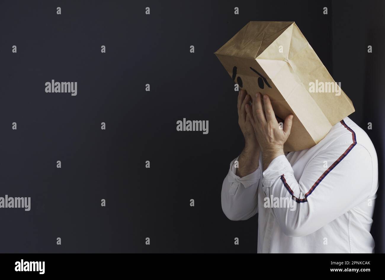 A sad man in a white shirt with a bag on his head, with a drawn crying ...