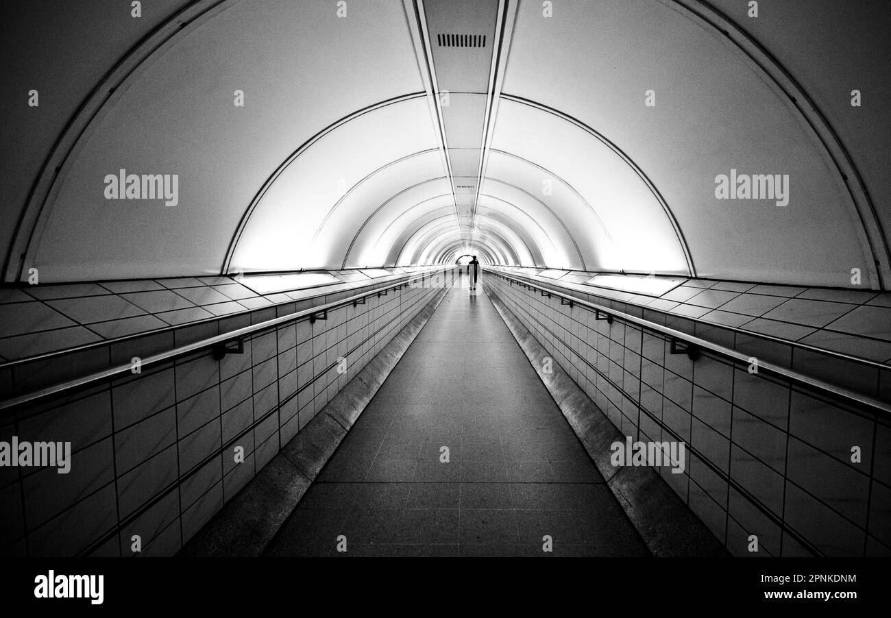 A grayscale of an underground train station interior, with a man ...