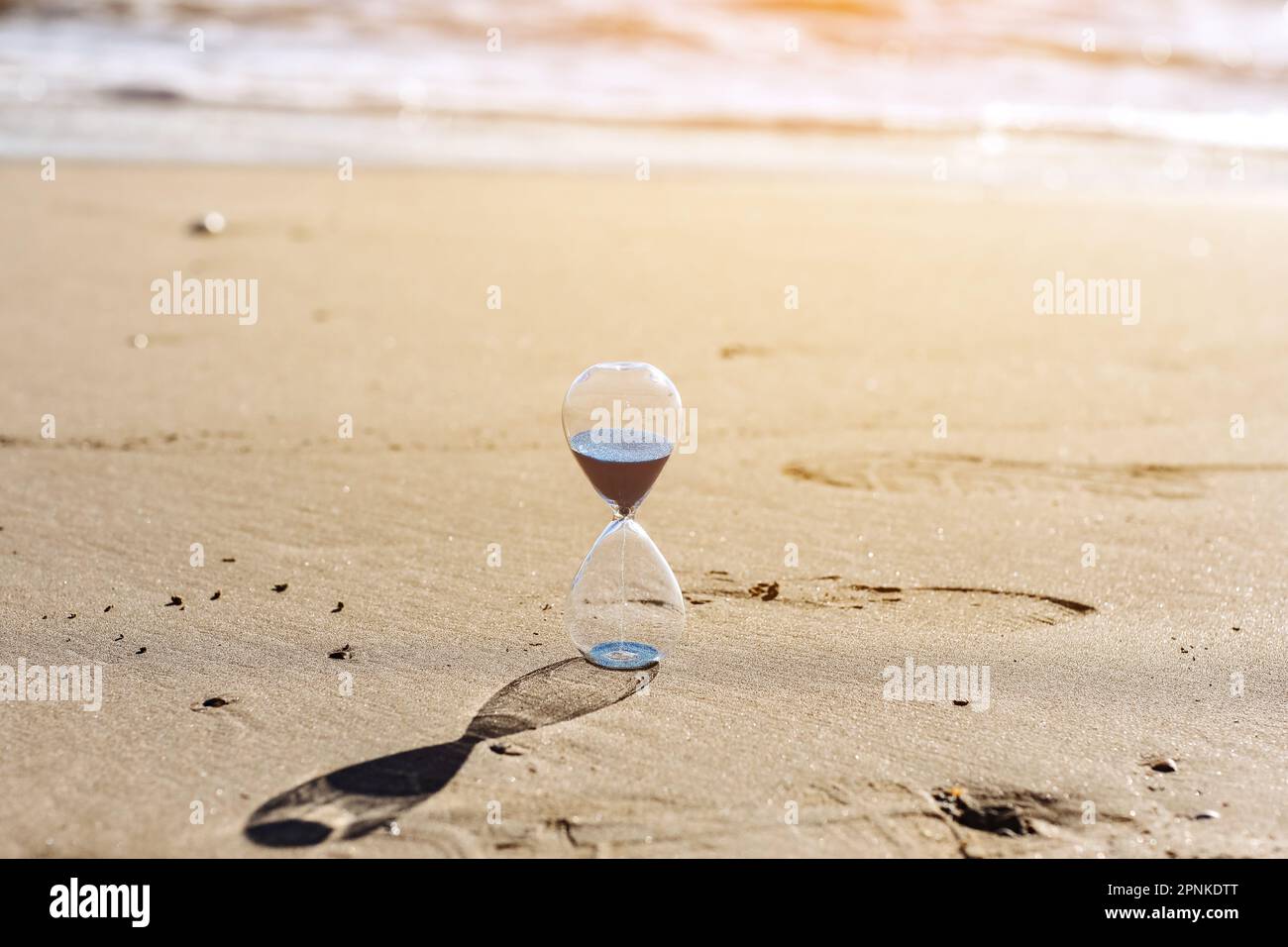 Hourglass with blue sand inside in a warm golden morning sunlight with ...