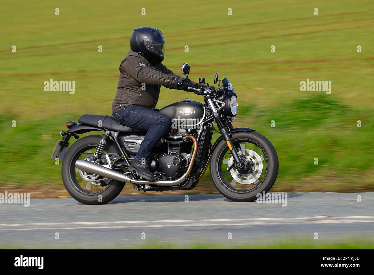 A motorcyclist riding a Triumph motorcycle along the B1222 towards ...