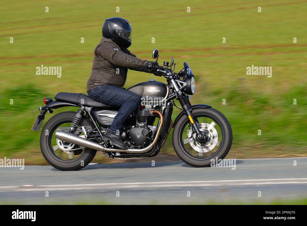 A motorcyclist riding a Triumph motorcycle along the B1222 towards ...