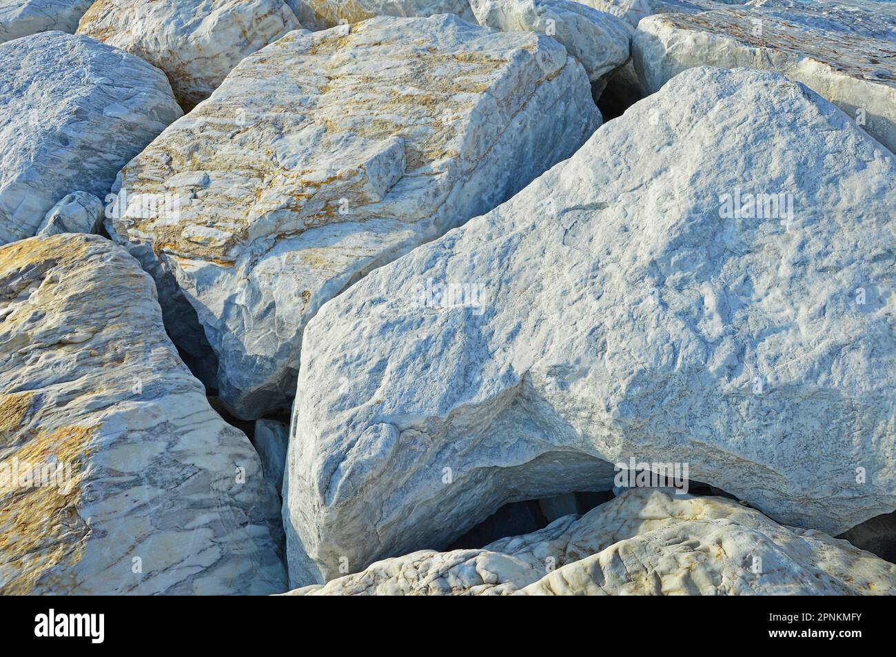 Piles of large marble boulders on the coast Stock Photo - Alamy