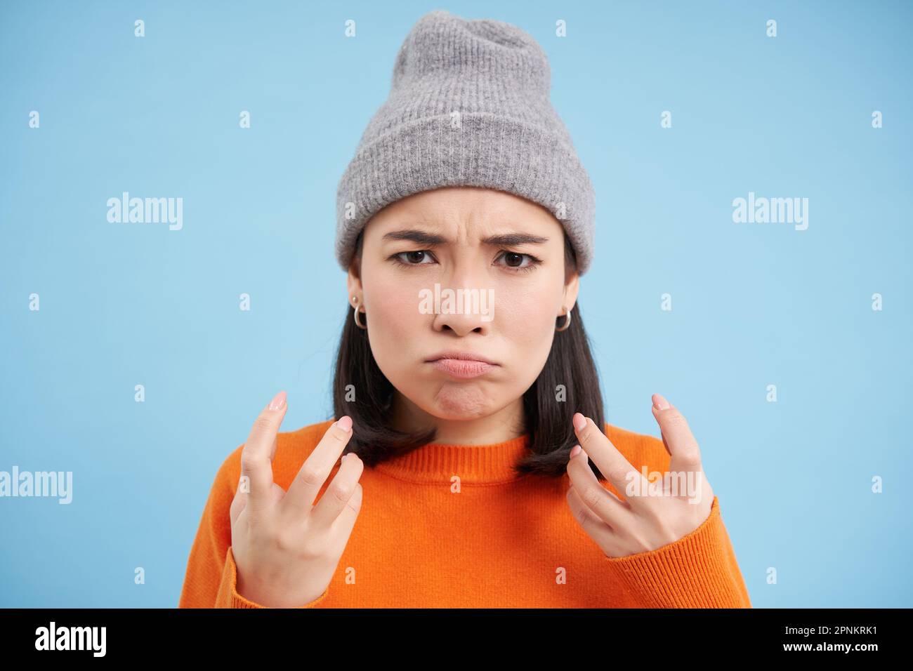 Close up portrait of annoyed asian girl, shakes hands and sulks, looks ...
