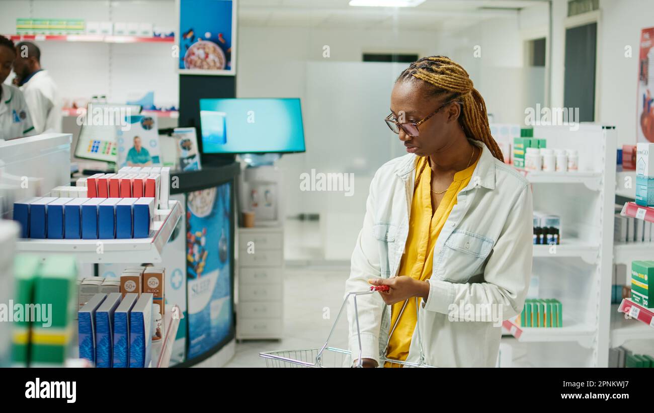 Female customer taking pills and medicine from shelves, looking at ...