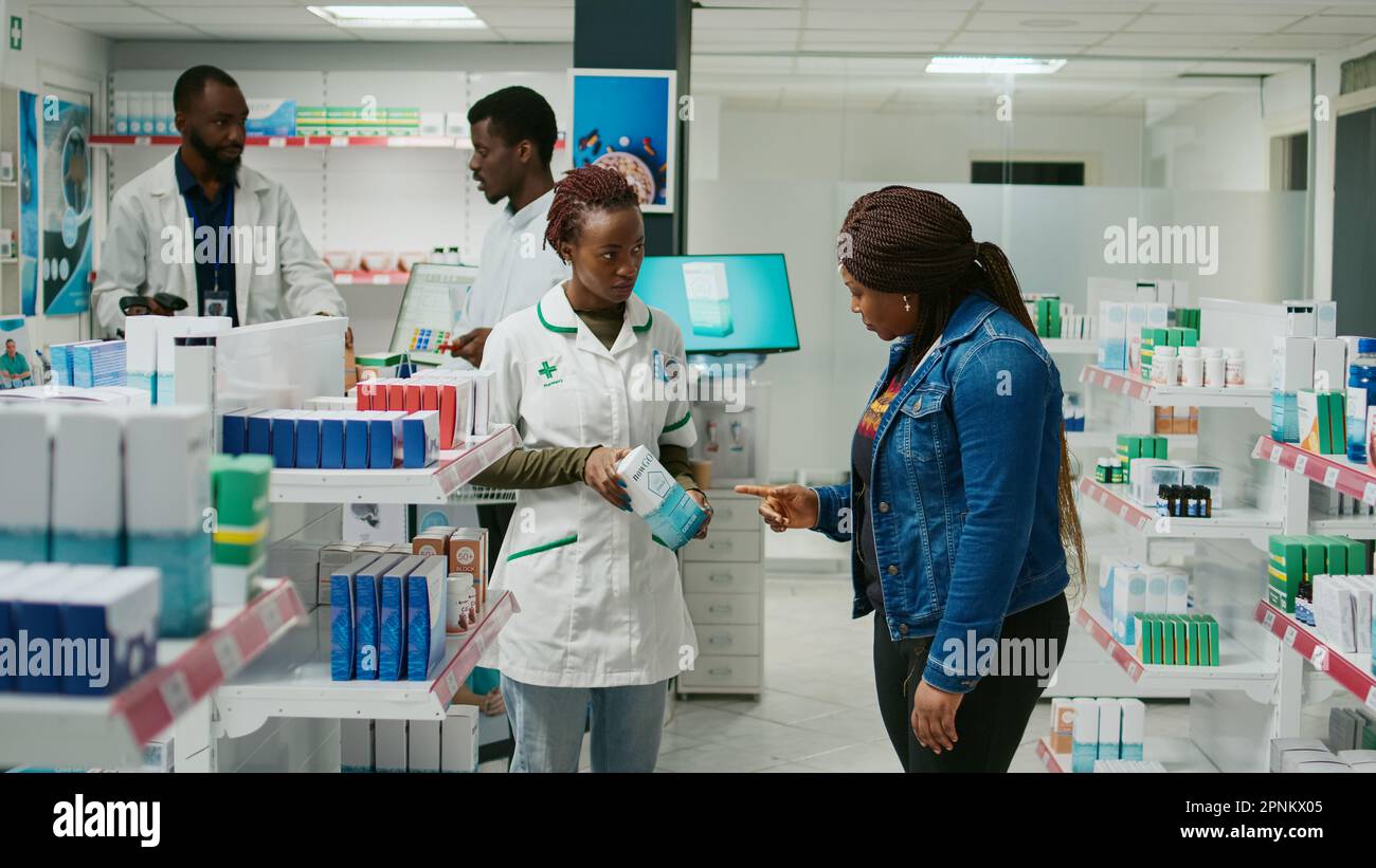 Female pharmacist helping customer with medicine, showing ...