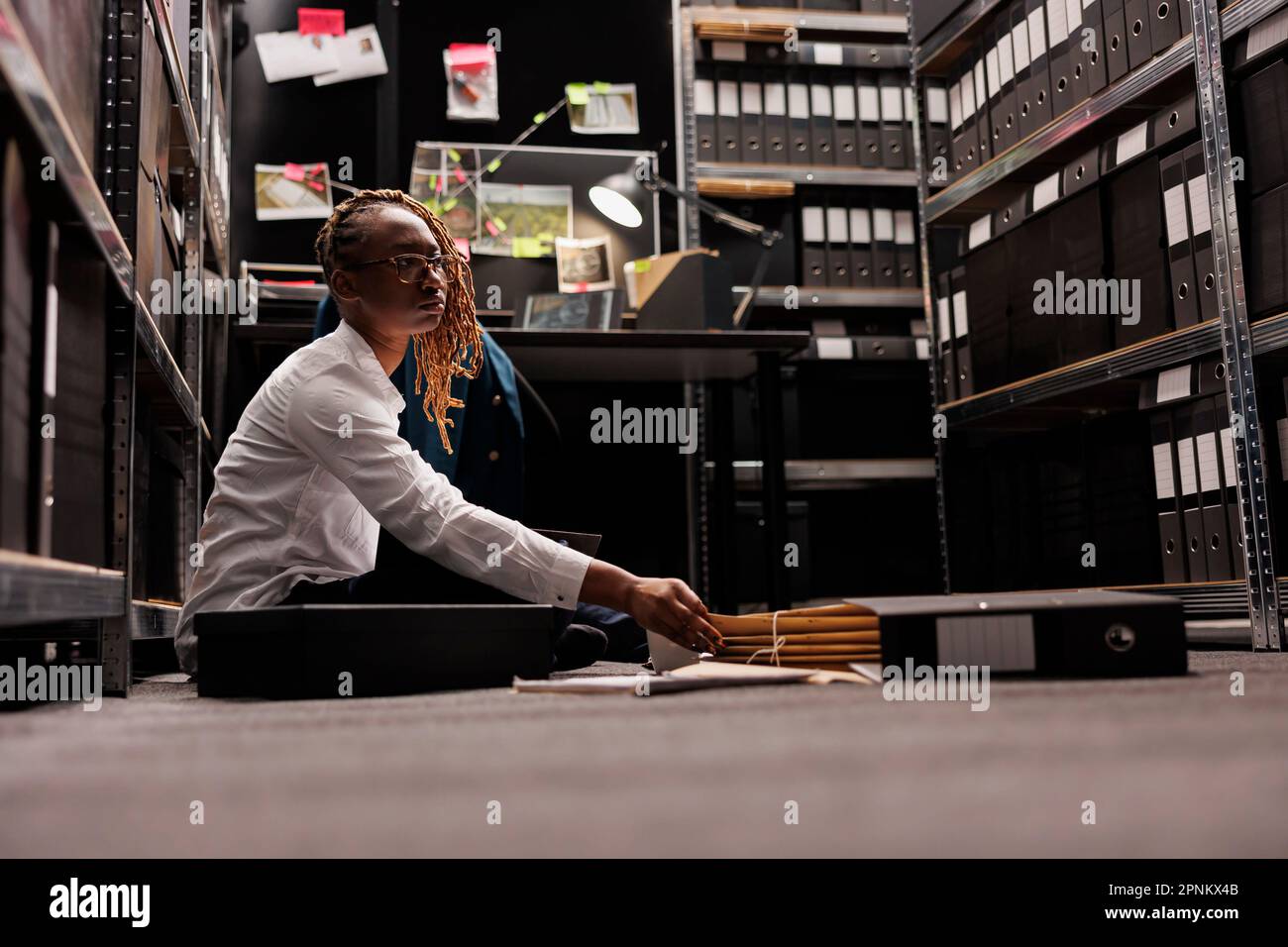 Private detective studying investigation reports on floor in agency ...