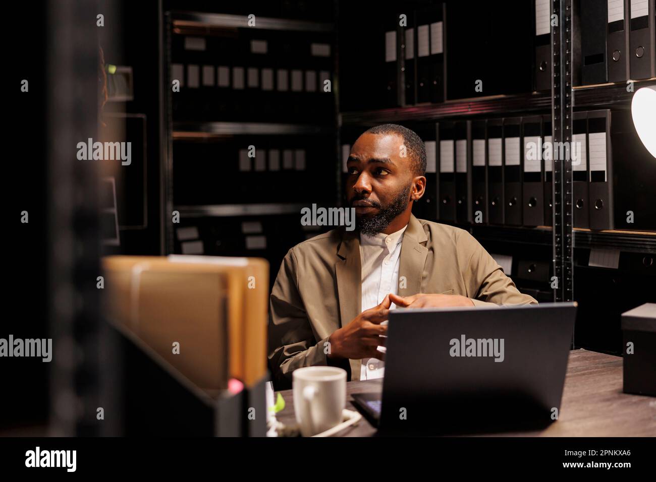 African american policeman working with archival crime case files and ...