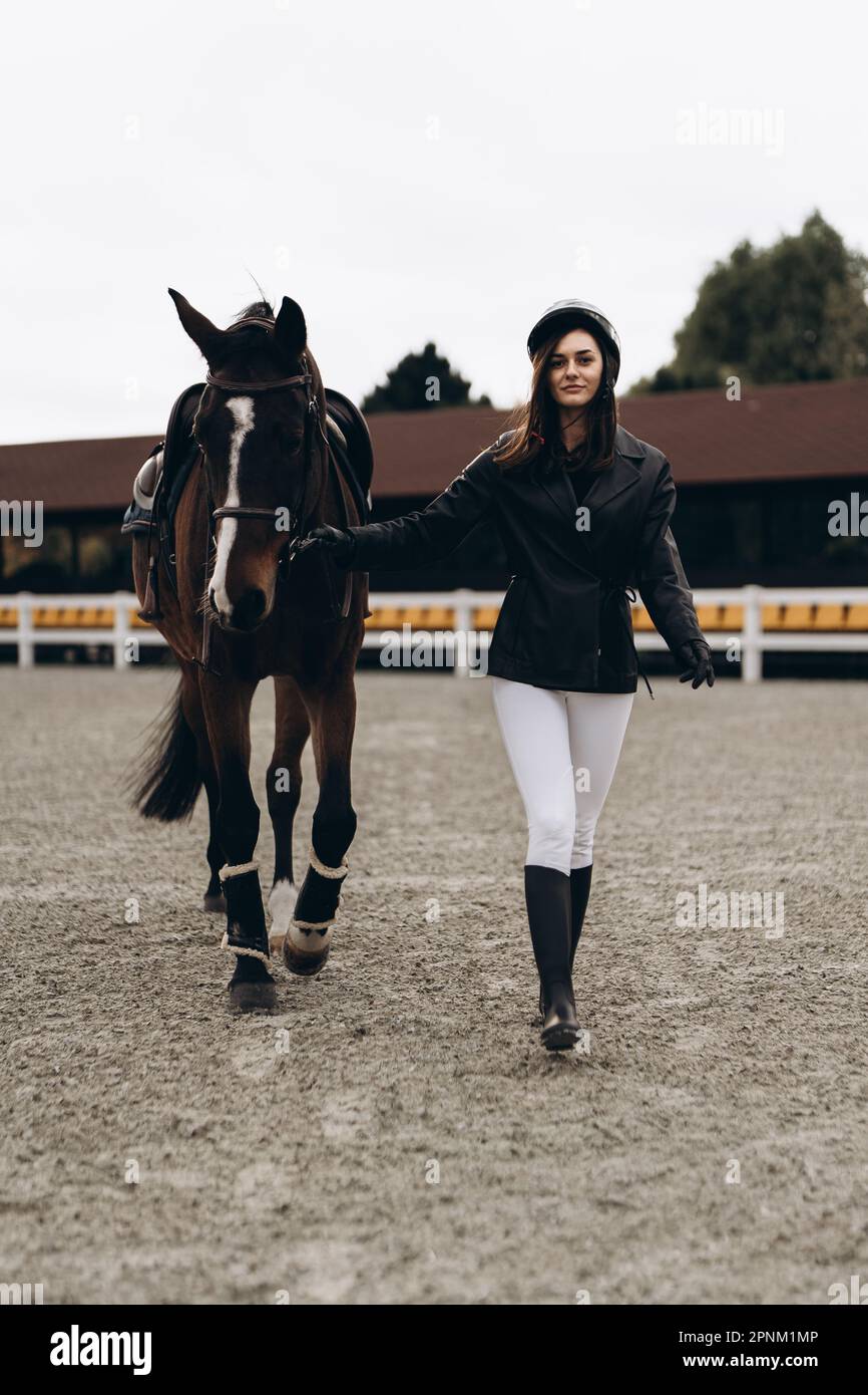 A young equestrian in uniform poses with a beautiful, majestic horse ...