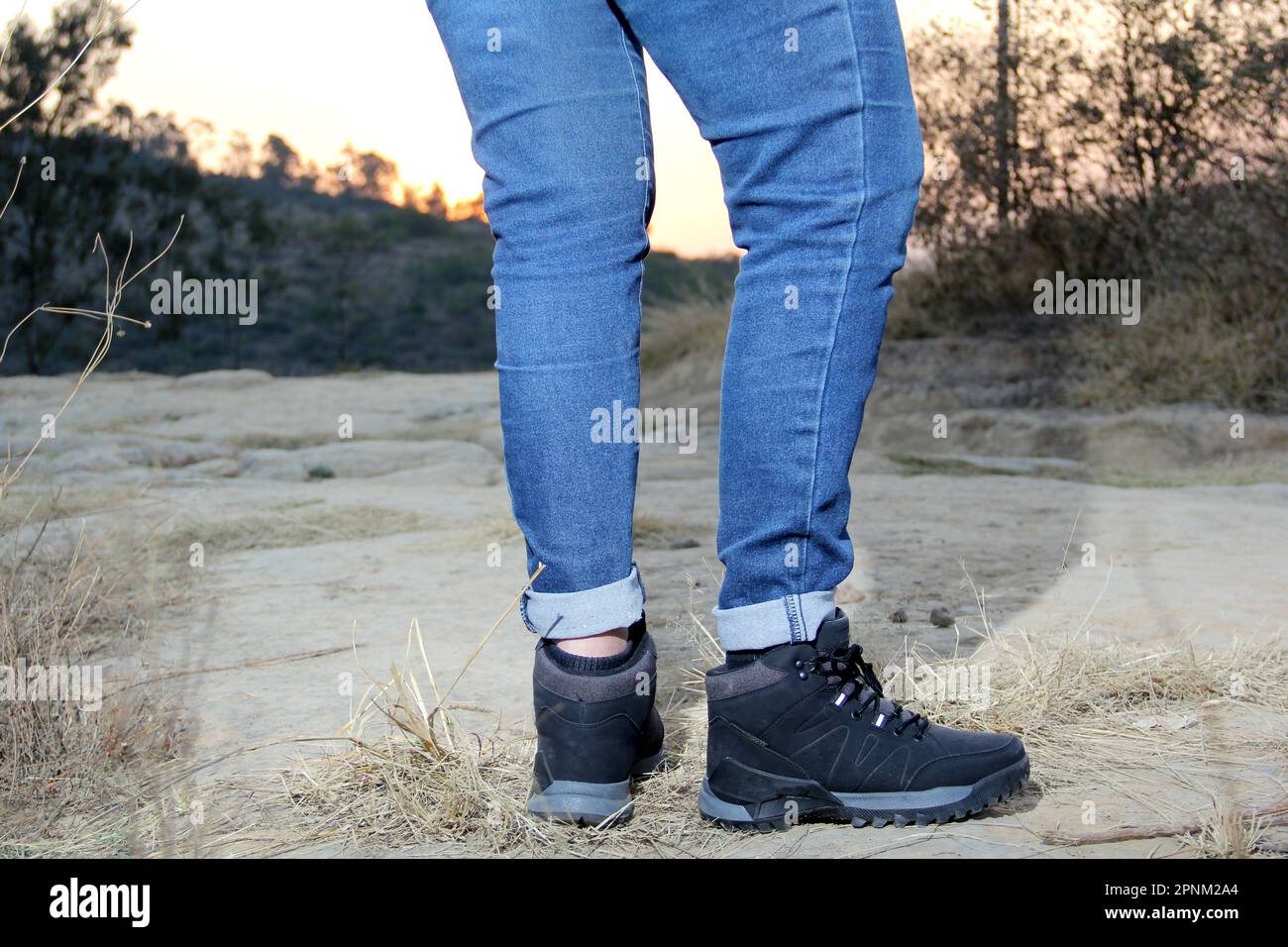 Legs with denim pants and black hiking boots in the middle of the field ...
