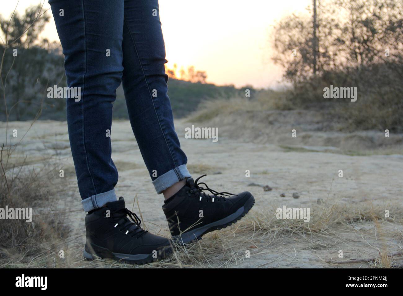 Legs with denim pants and black hiking boots in the middle of the field ...