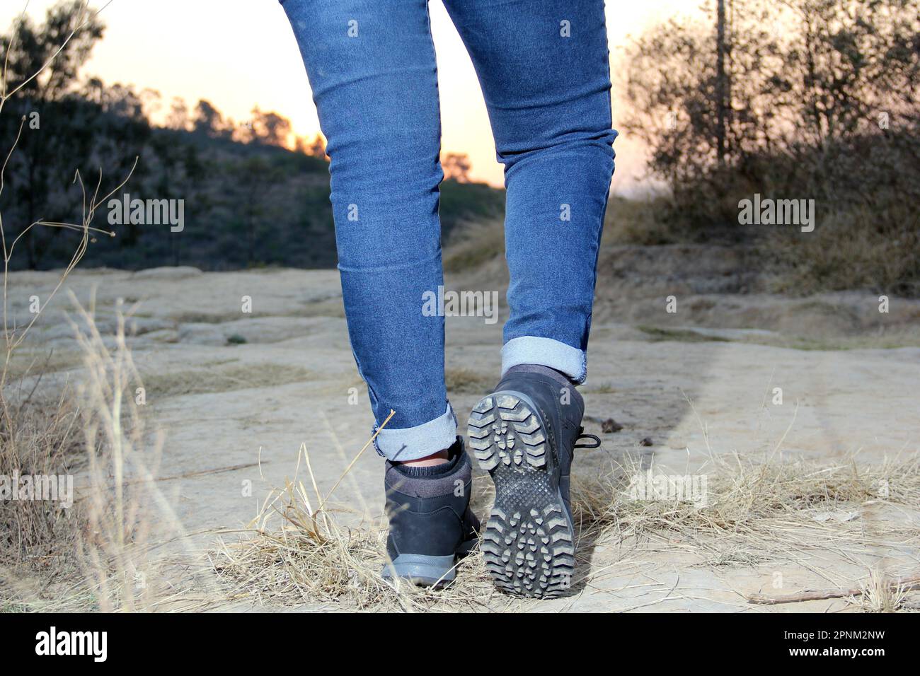 Legs with denim pants and black hiking boots in the middle of the field ...