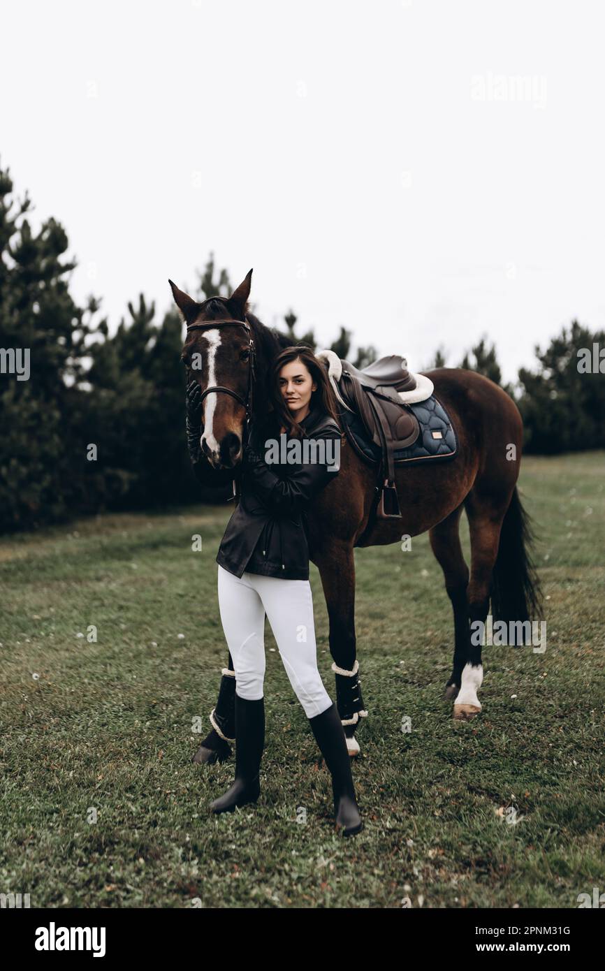A young equestrian in uniform poses with a beautiful, majestic horse ...
