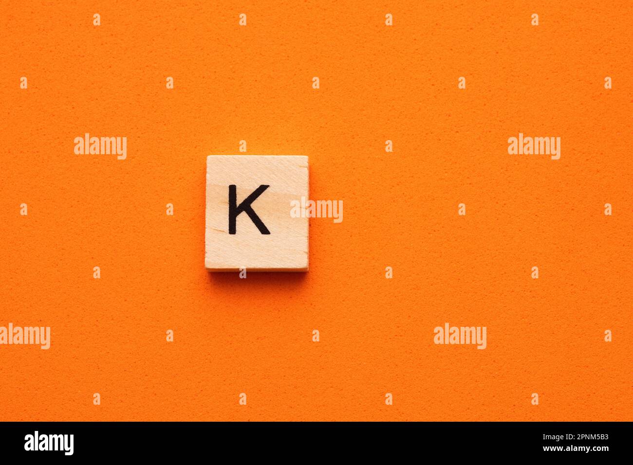 Alphabet letter K on wooden square tile - Orange foamy background Stock ...