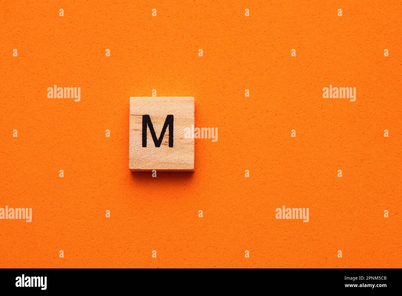 Alphabet letter M on wooden square tile - Orange foamy background Stock ...