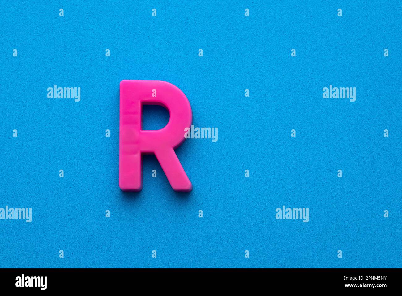 Alphabet letter R - Pink plastic piece on blue foamy background Stock ...