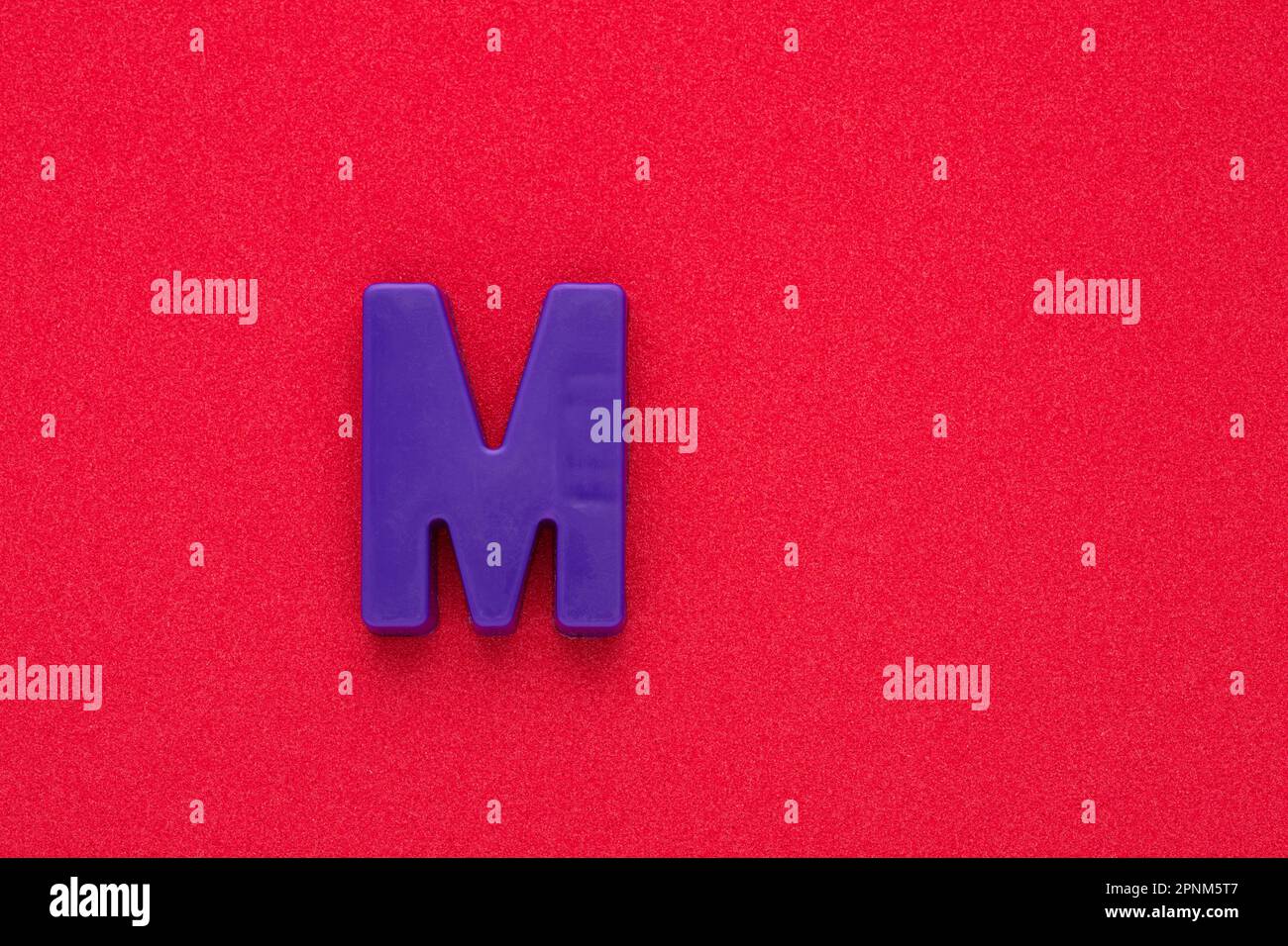 Alphabet letter M - Violet colored plastic piece on red 032 c foamy ...