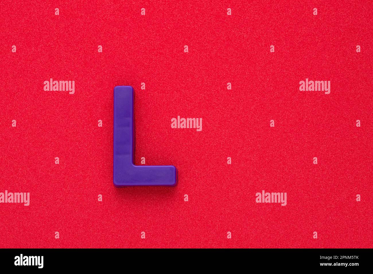Plastic letter L uppercase in violet color on a red 032 c foamy ...