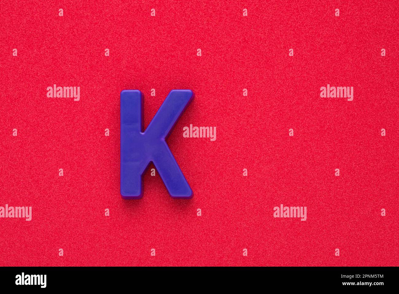Alphabet letter K - Violet colored plastic piece on red 032 c foamy ...