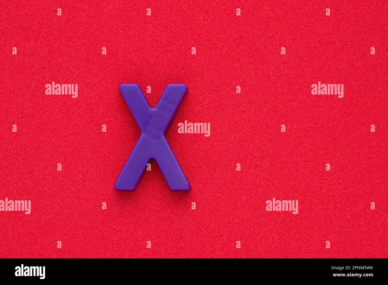 Alphabet letter X - Violet colored plastic piece on red 032 c foamy ...