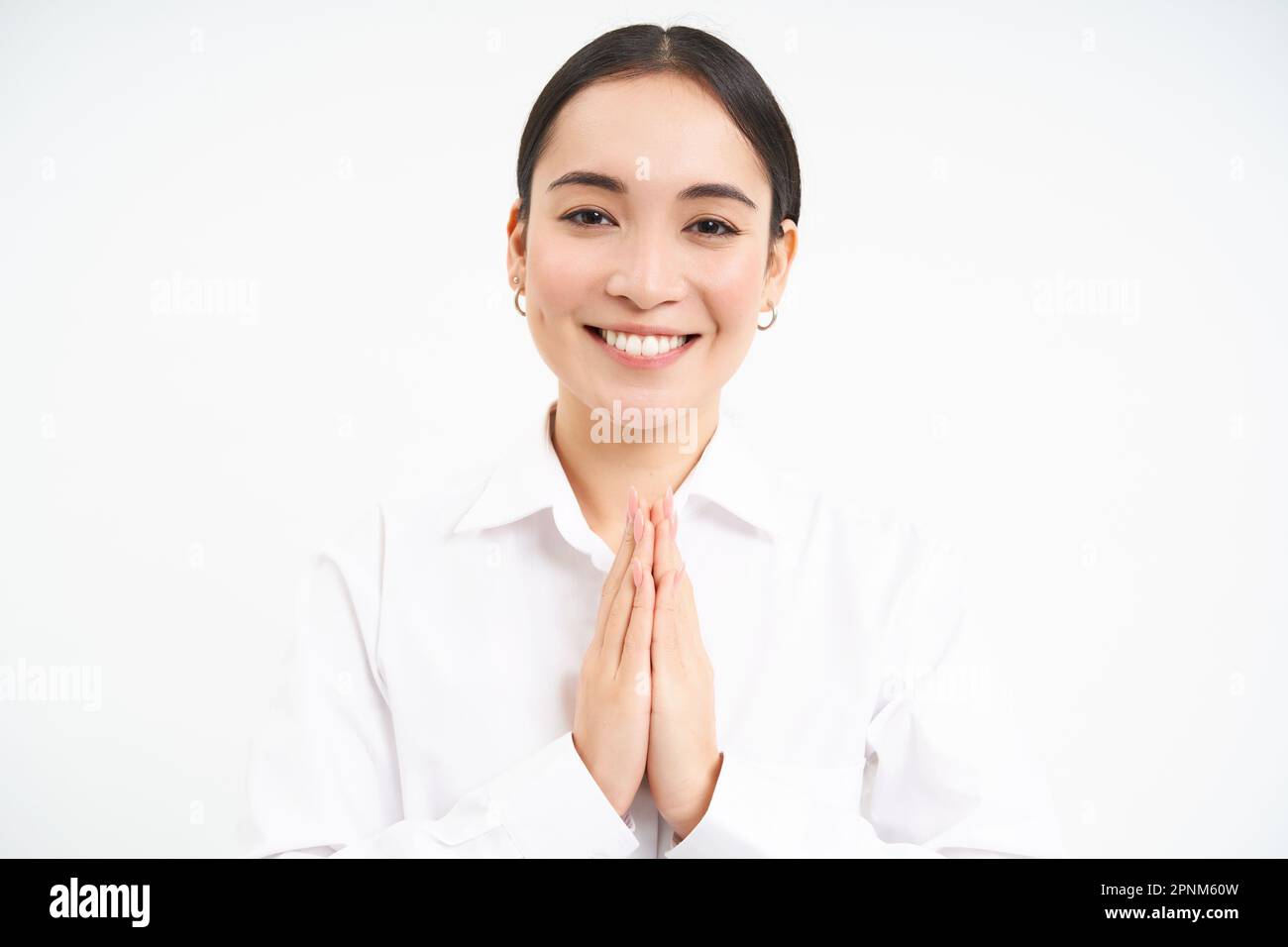 Namaste. Smiling japanese woman shows hands in pray, says thank you, bows politely, stands over ...