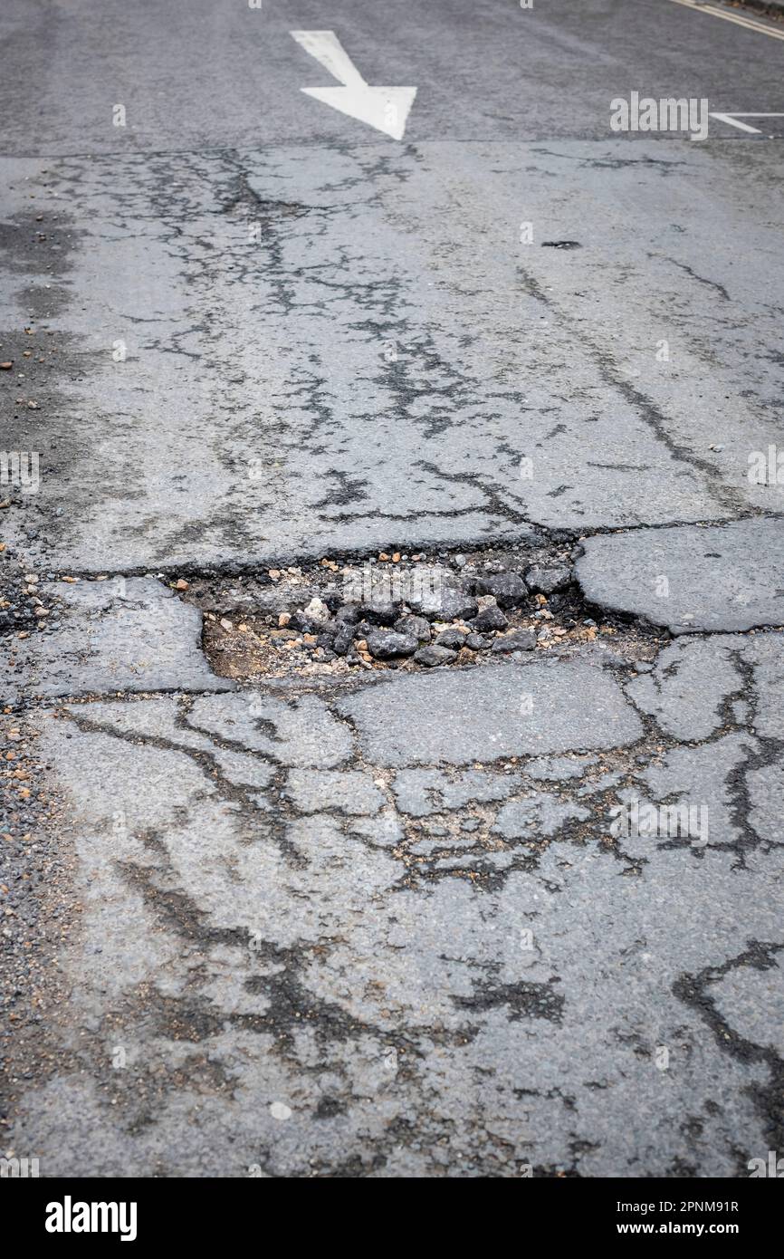 View of a large pothole residential street, tarmac broken with a large ...