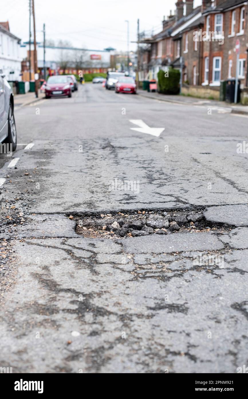View of a large pothole residential street, tarmac broken with a large ...